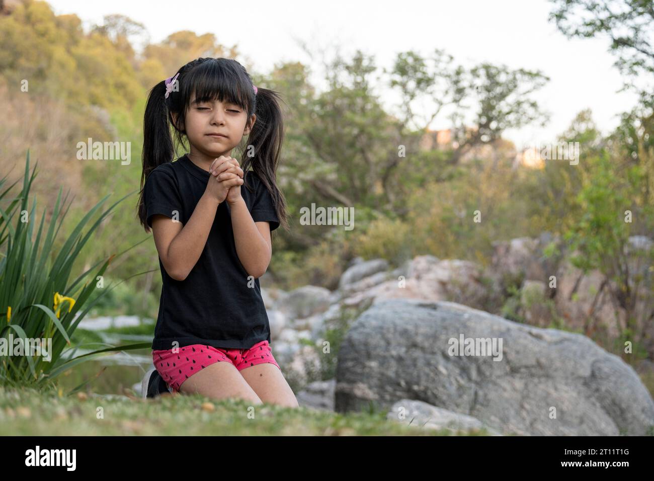 Little girl praying in a natural environment Stock Photo - Alamy