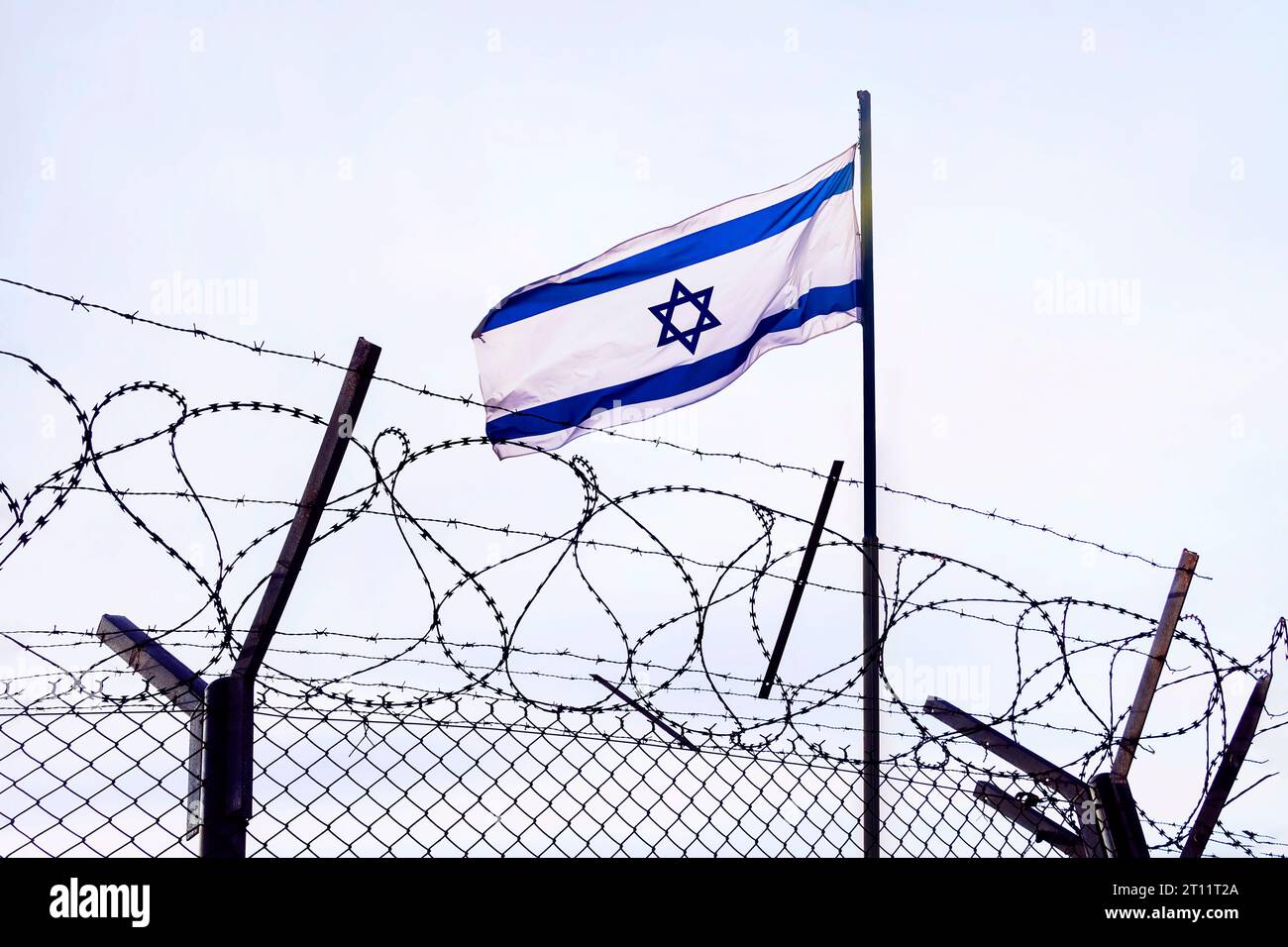 View of israeli flag behind barbed wire against cloudy sky. border post ...