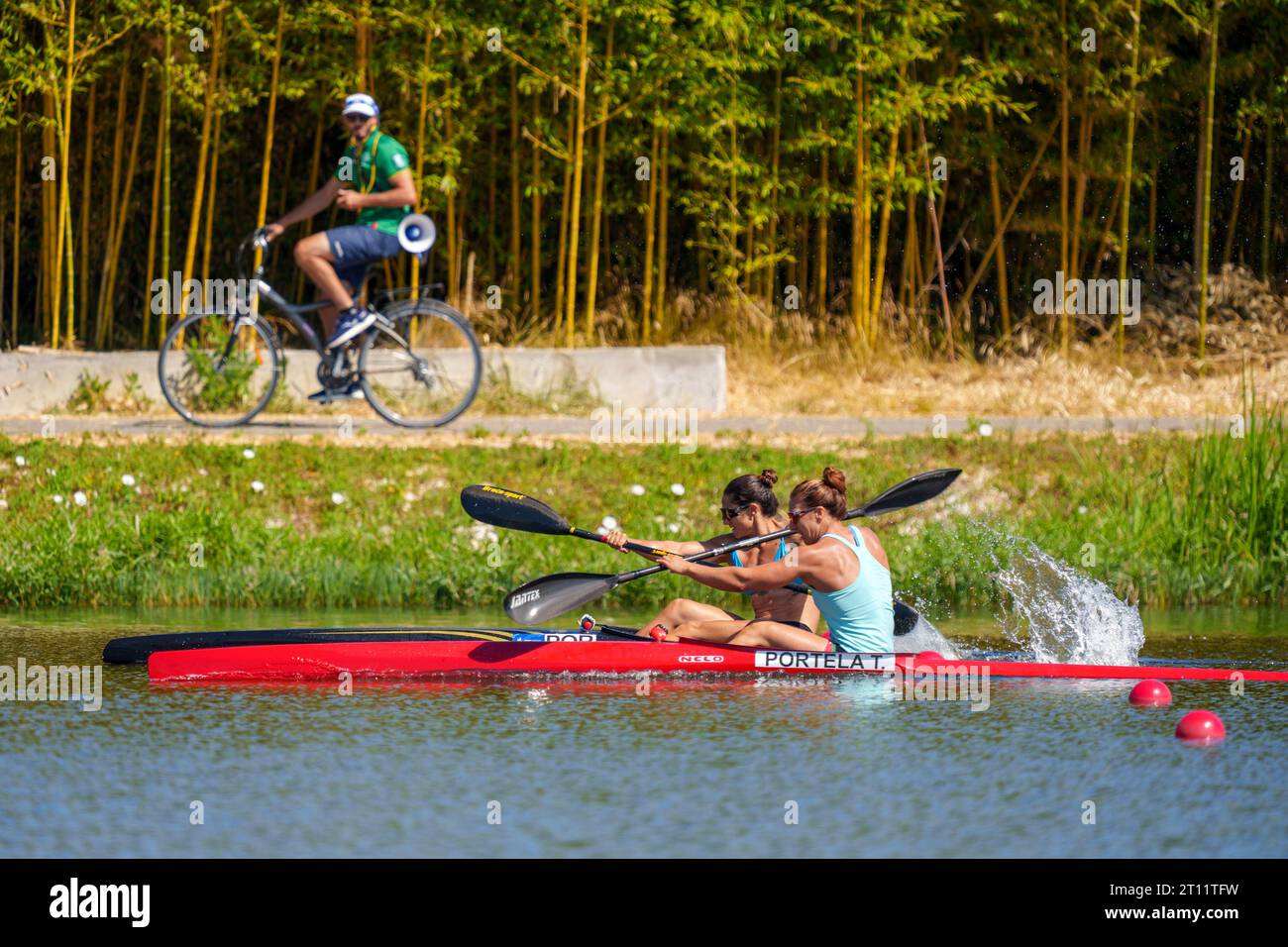 Female canoeists training hard in practice while their coach rides ...