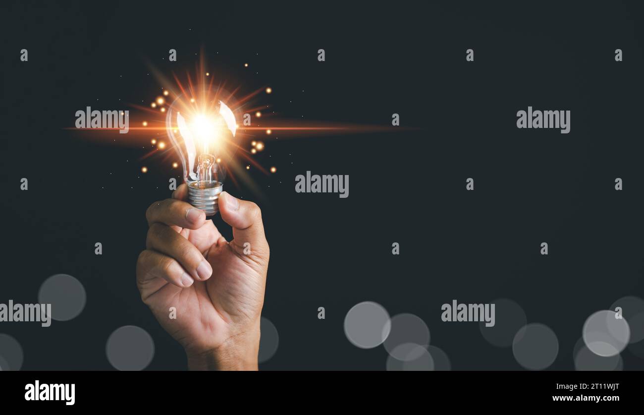A hand holding a glowing light bulb, signifying the connection between ...