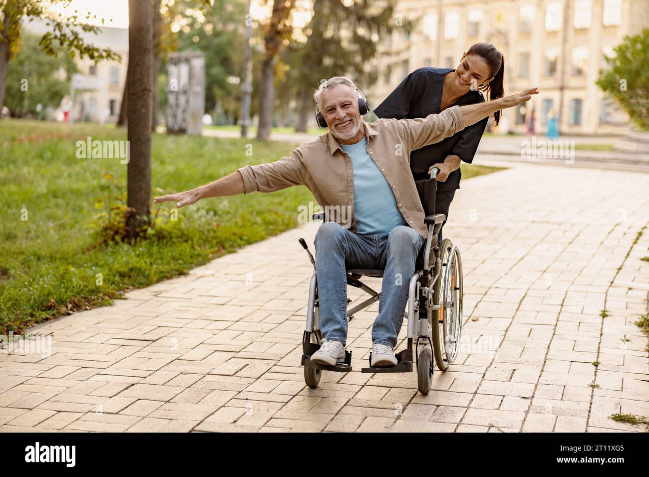 Joyful mature disabled man in wheelchair wearing headphones having fun ...