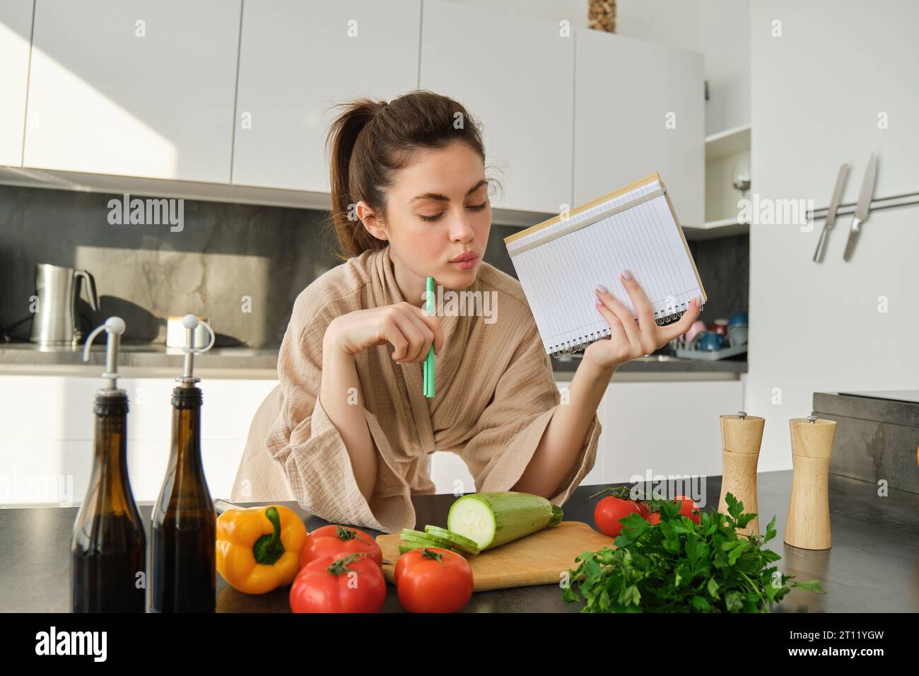 Portrait of woman checking grocery list, looking at vegetables, holding ...