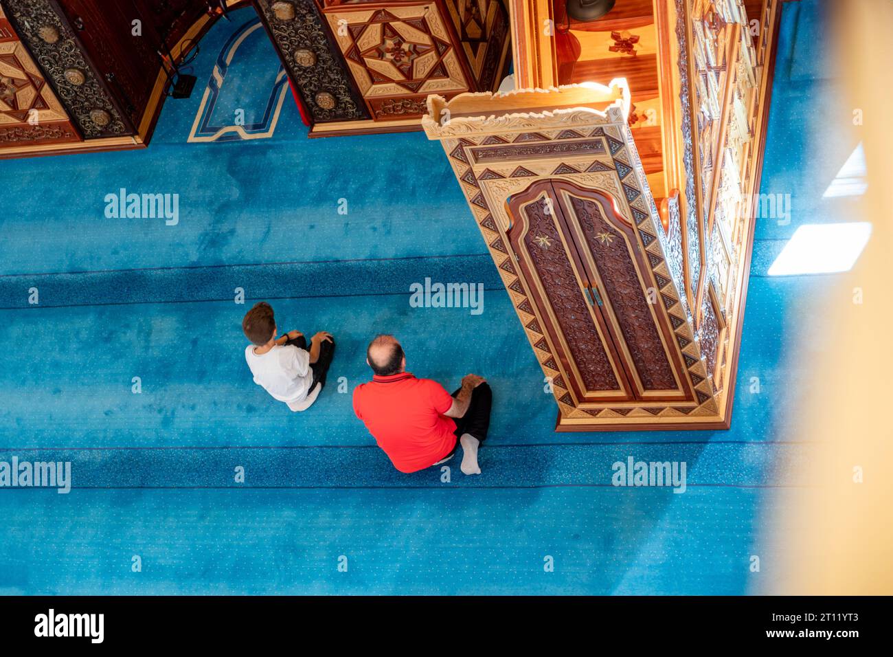 Adult and child are praying inside mosque with blue carpet Stock Photo ...