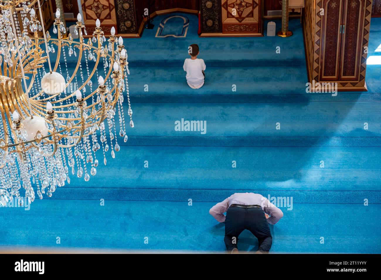Adult and child are praying inside mosque with blue carpet Stock Photo ...