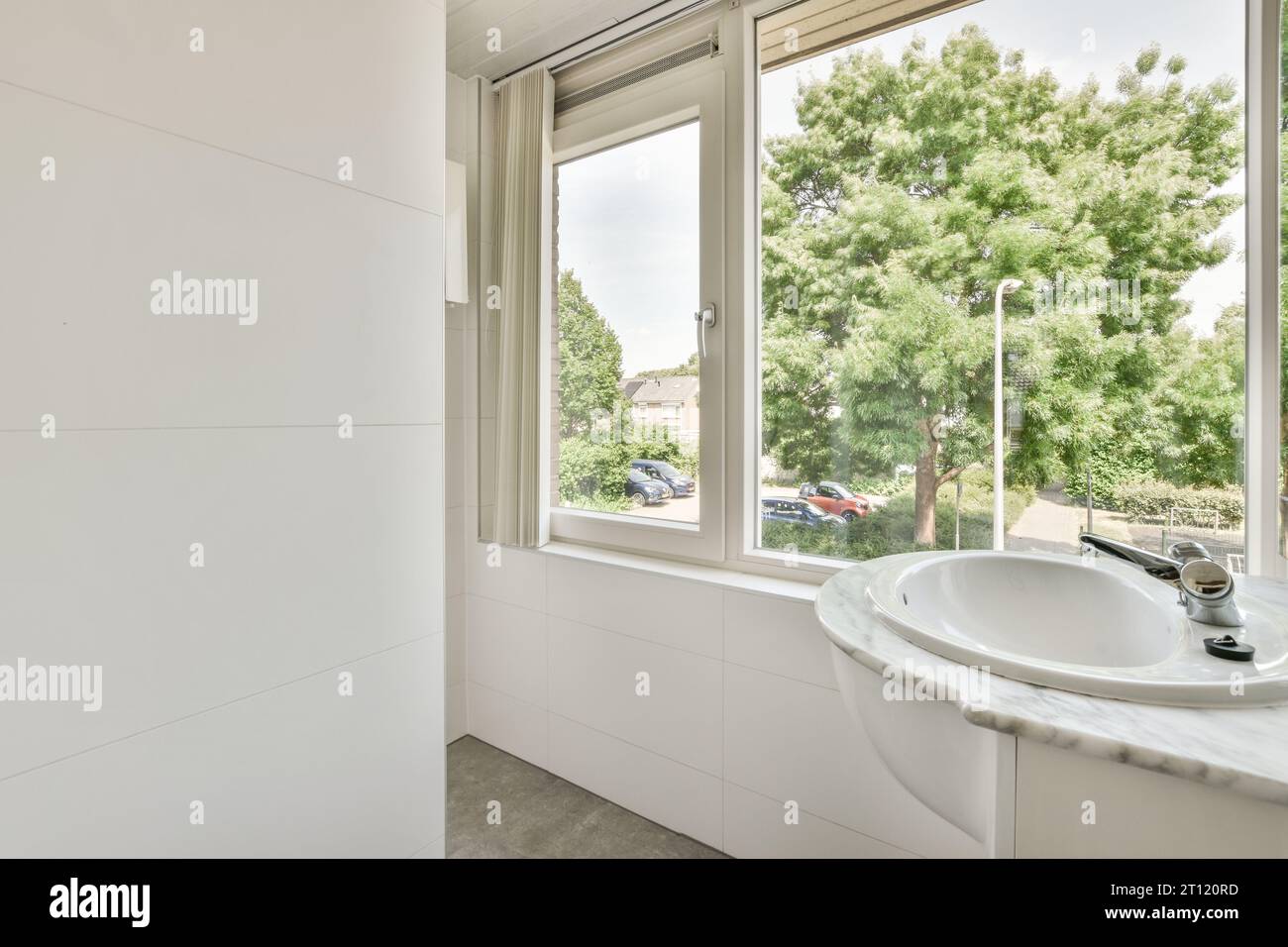 a bathroom with a sink and large window looking out at the trees ...