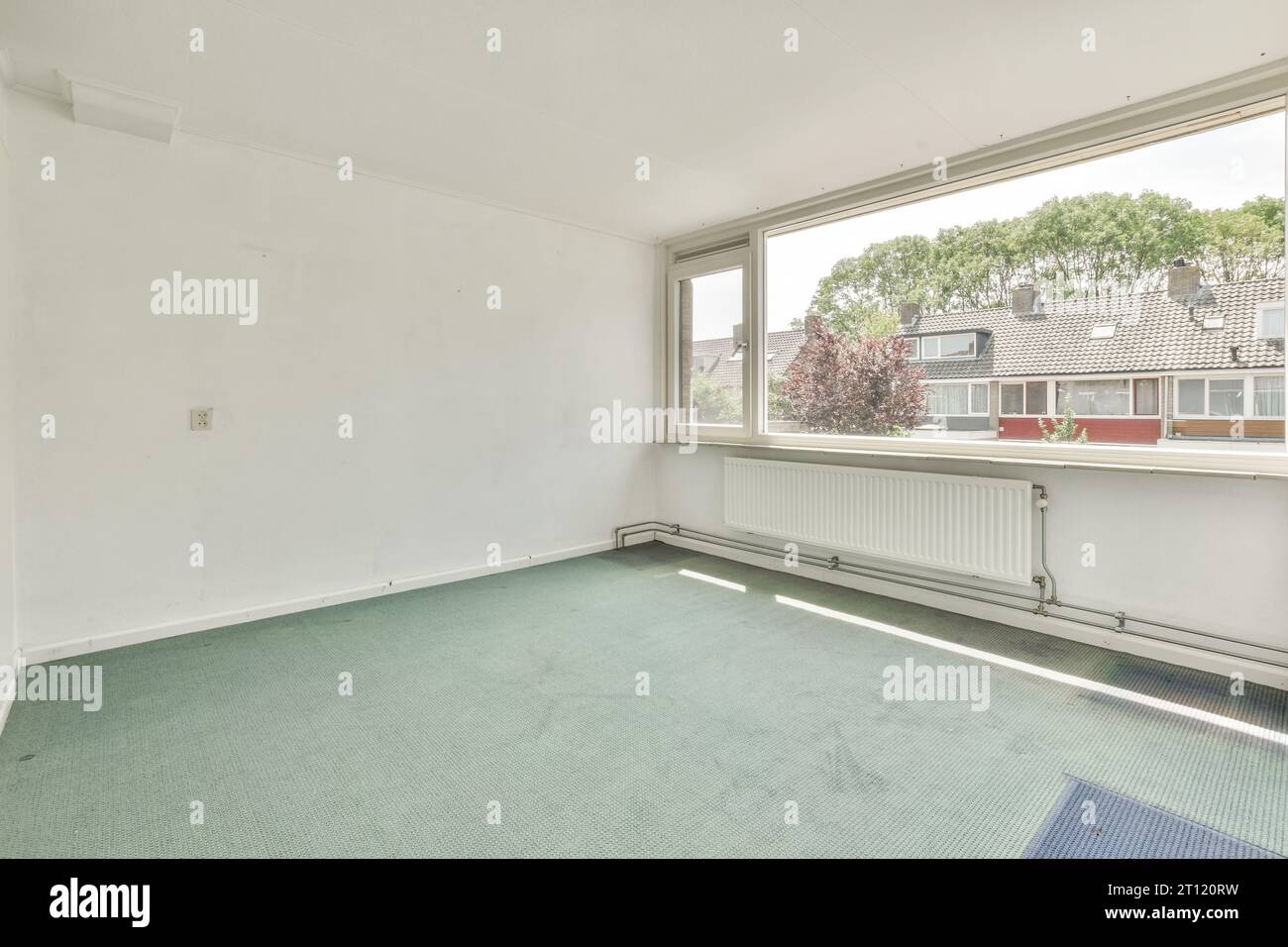 an empty room with green carpet and white walls, looking out onto the ...