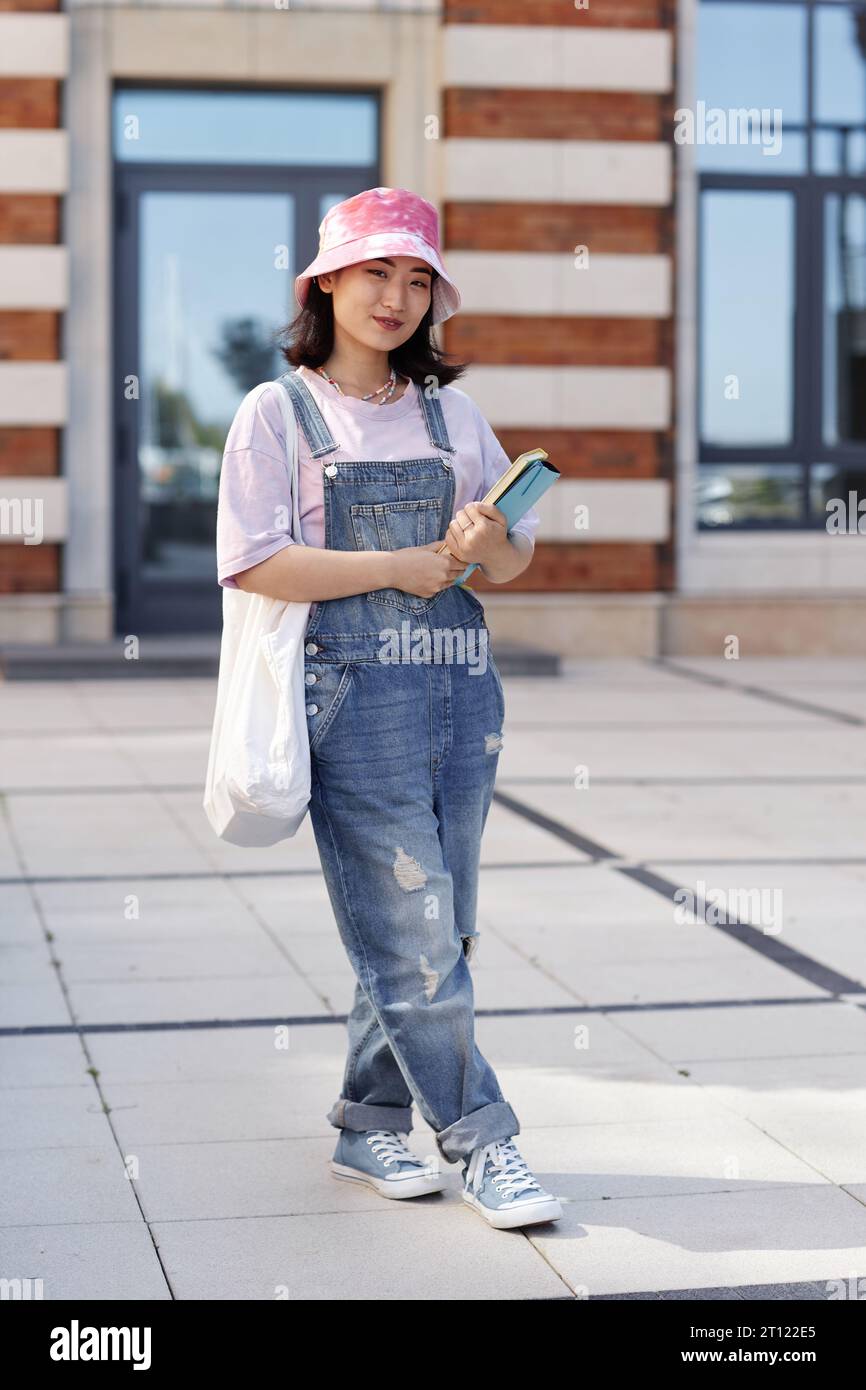 Vertical full length portrait of fun young Asian woman wearing denim ...
