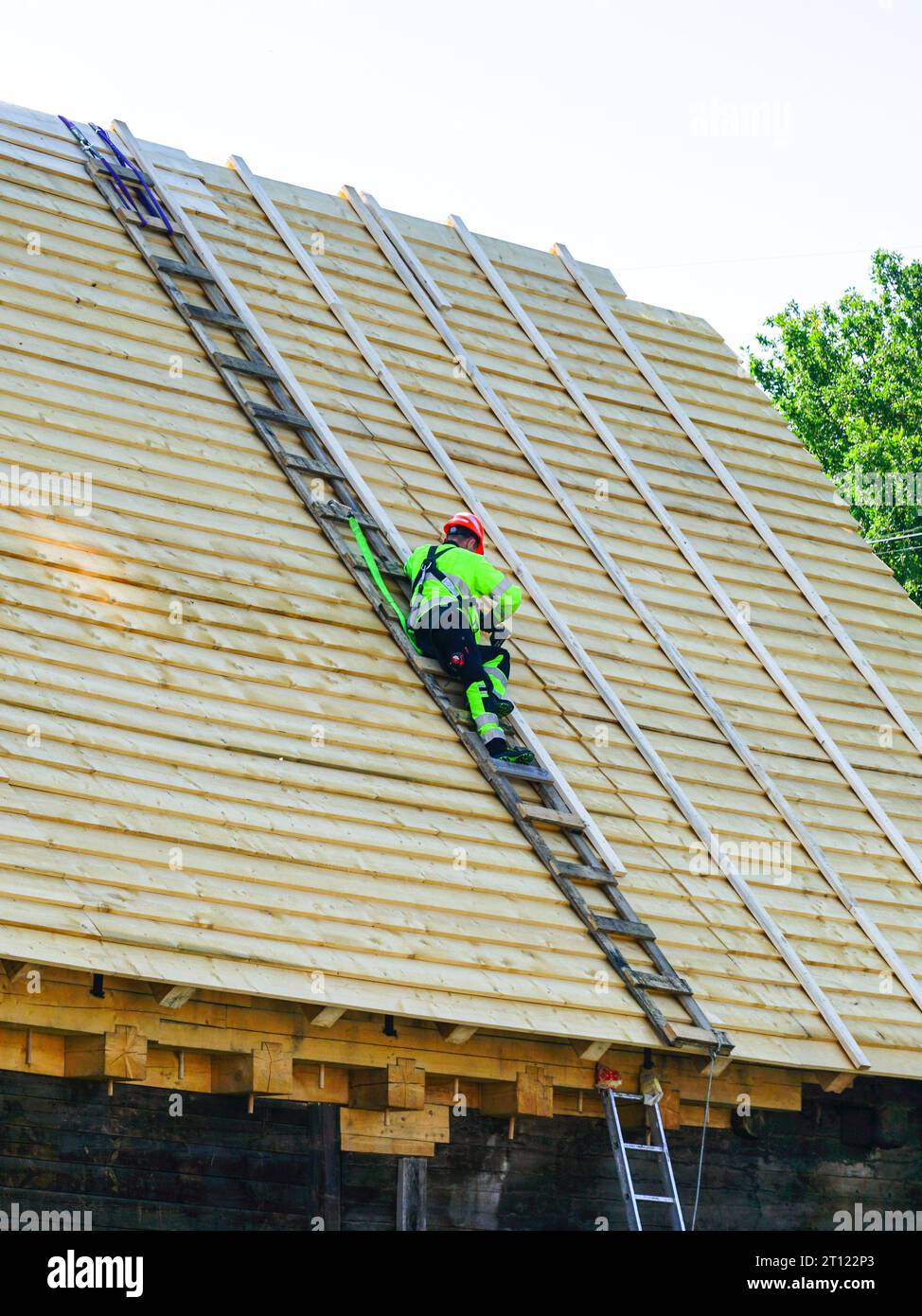 Worker nails new clapboards layer on roof before installing clay tiles ...