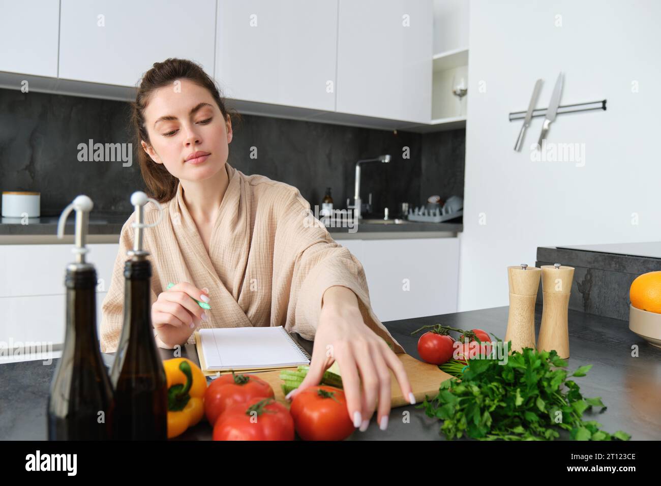 Portrait of woman sitting with groceries, making list for shopping ...