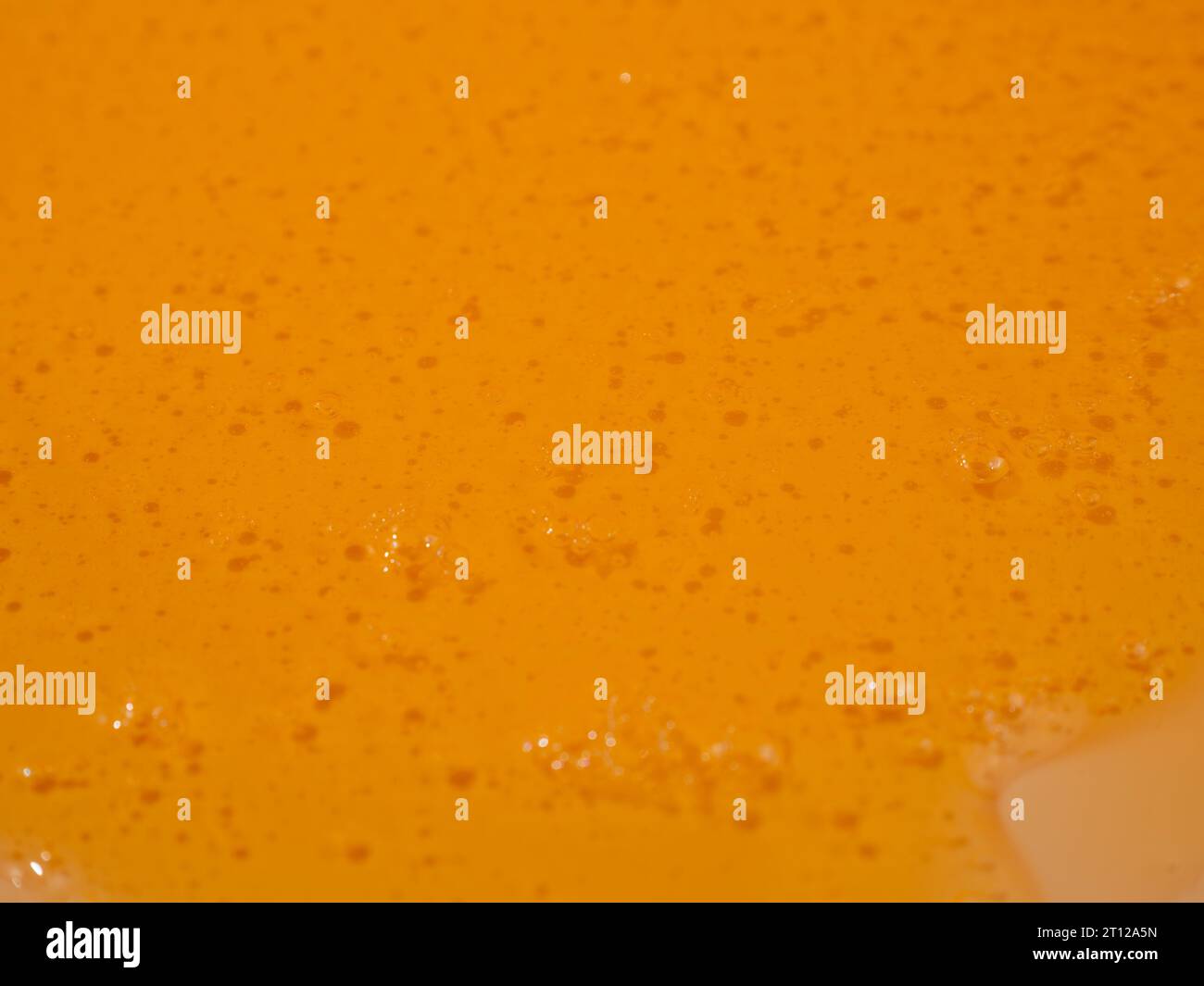 Liquid shower gel flows gracefully across a bright orange background ...