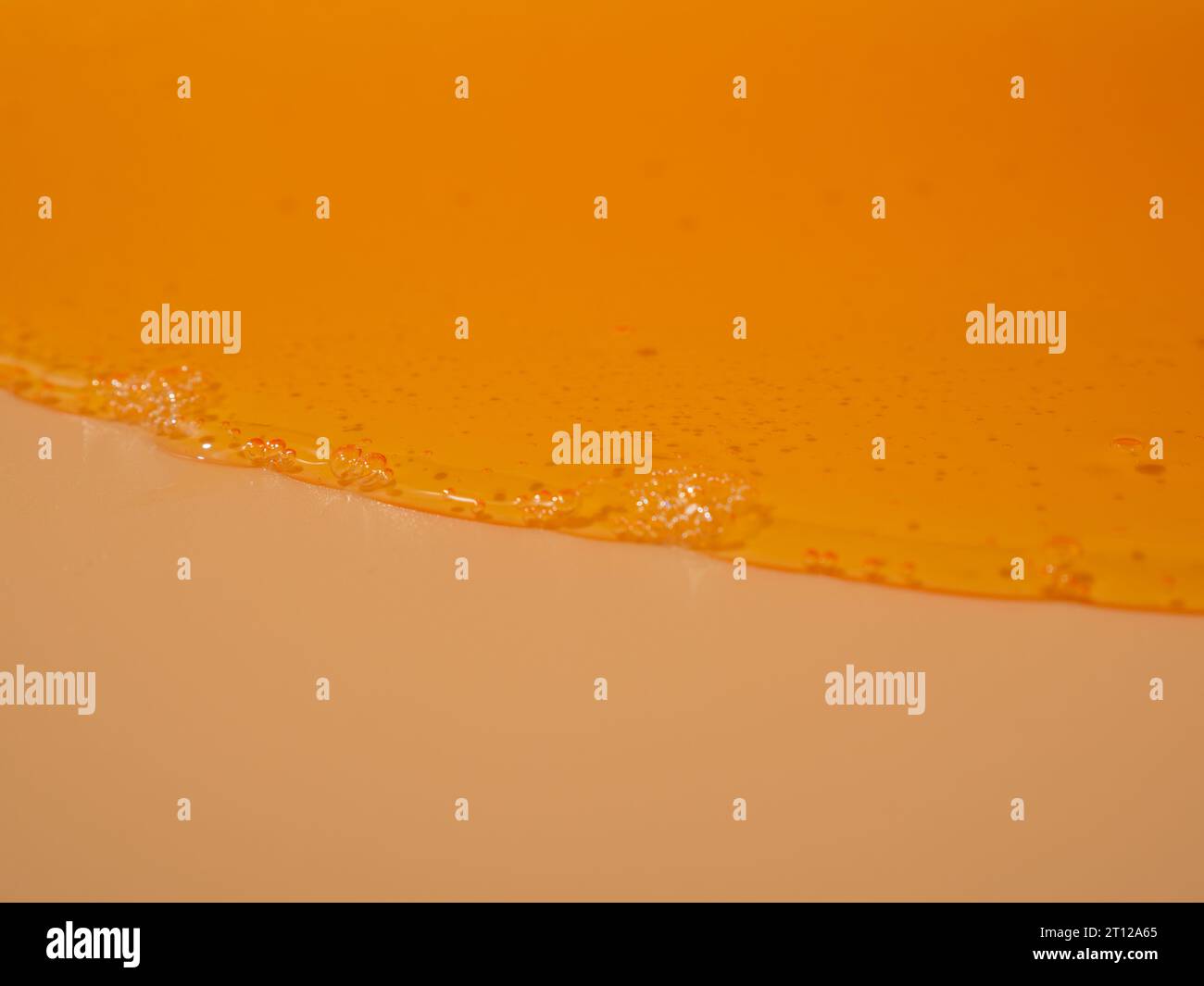 Liquid shower gel flows gracefully across a bright orange background ...