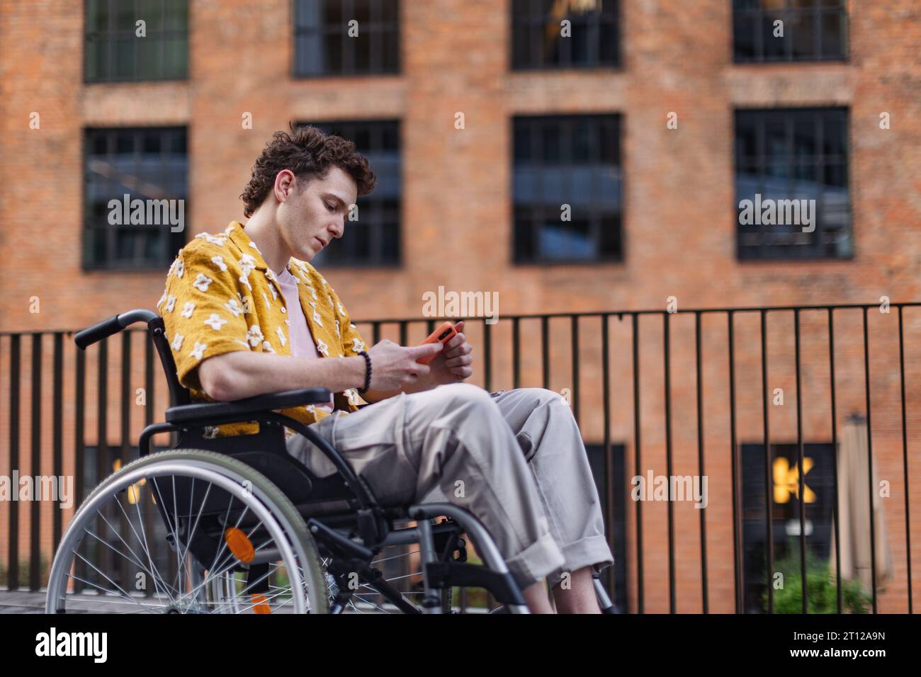 Gen Z boy in wheelchair in the city using smartphone. Inclusion ...