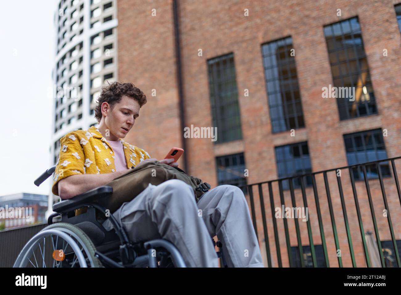 Gen Z boy in wheelchair in the city using smartphone. Inclusion ...