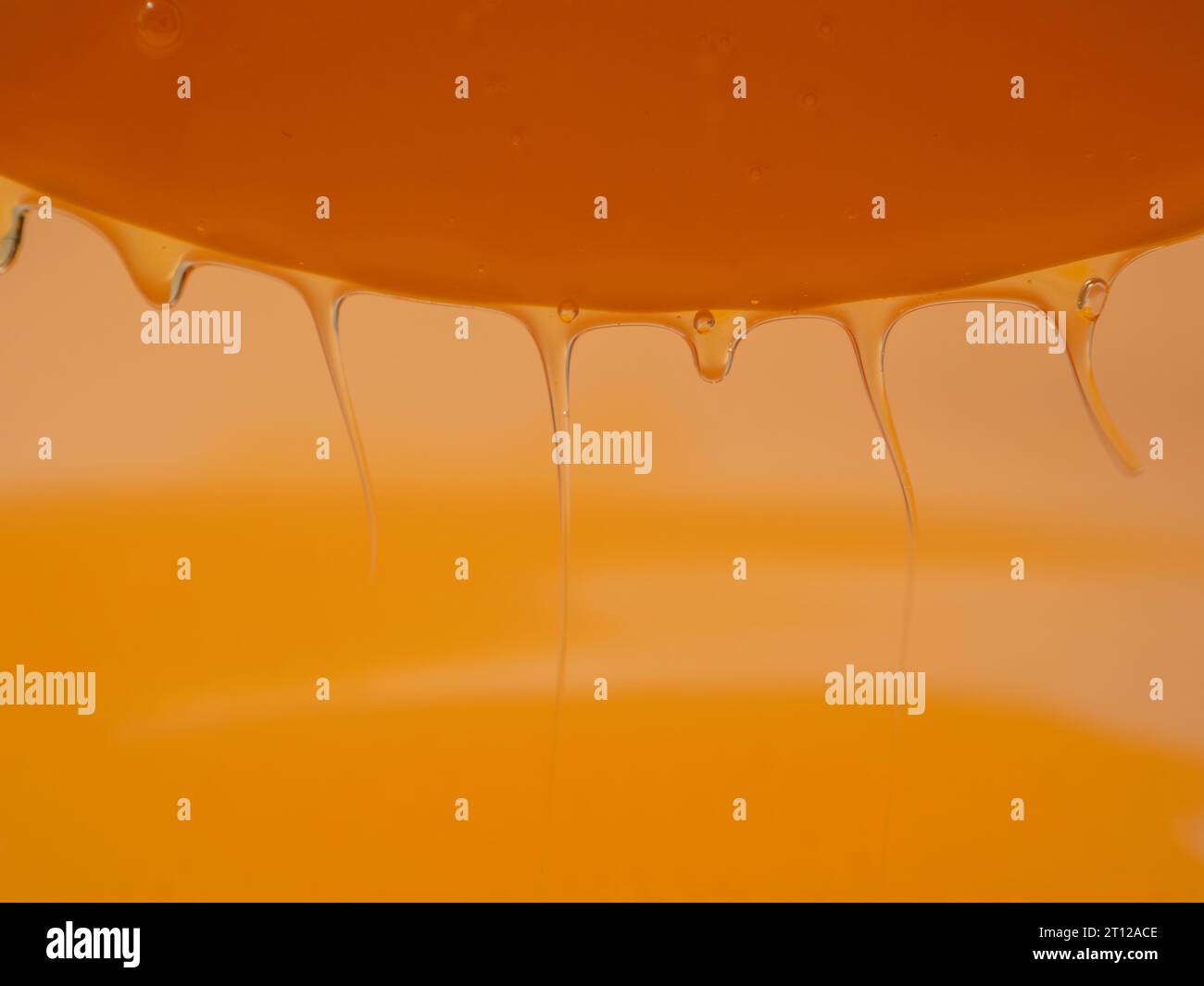 Liquid shower gel flows gracefully across a bright orange background ...