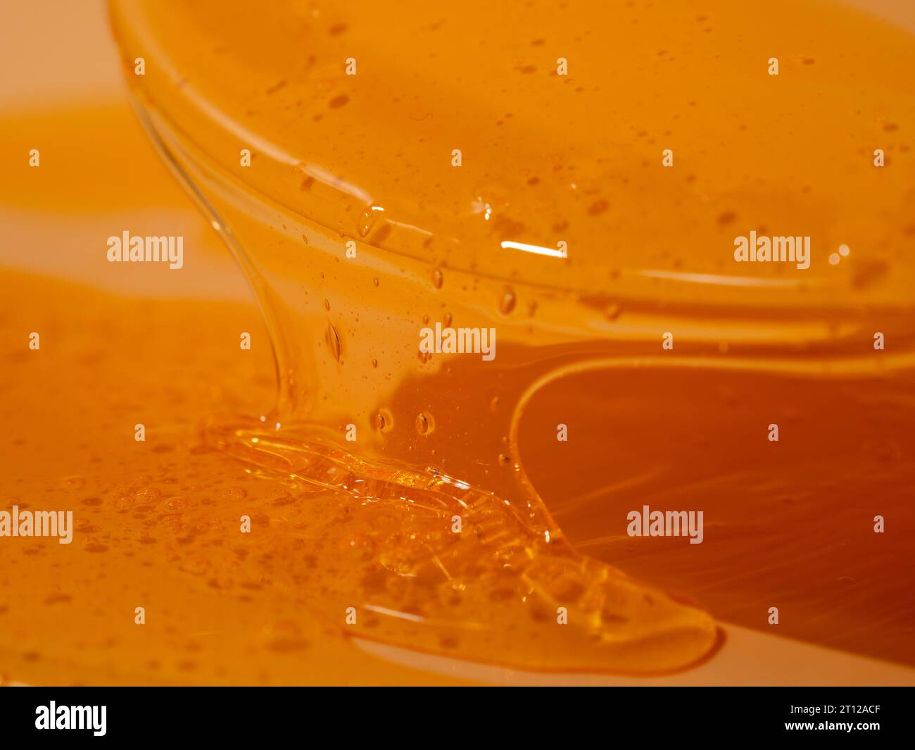 Liquid shower gel flows gracefully across a bright orange background ...