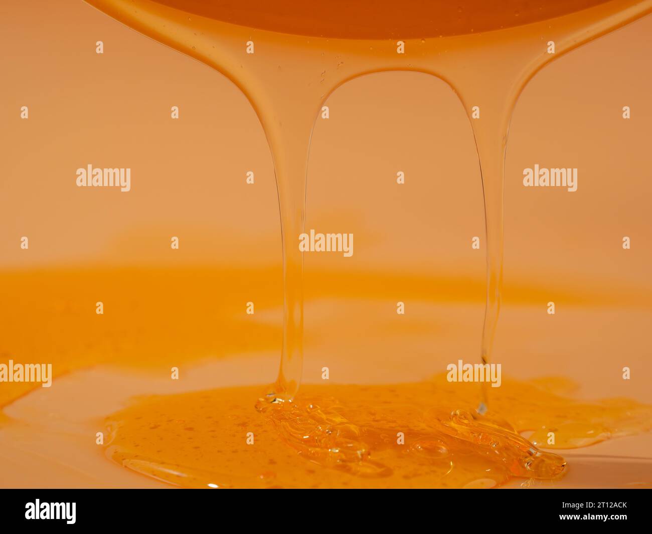 Liquid shower gel flows gracefully across a bright orange background ...