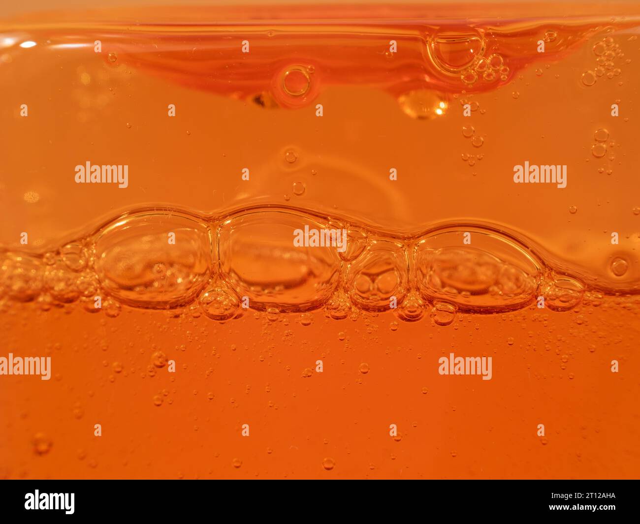 Liquid shower gel flows gracefully across a bright orange background ...