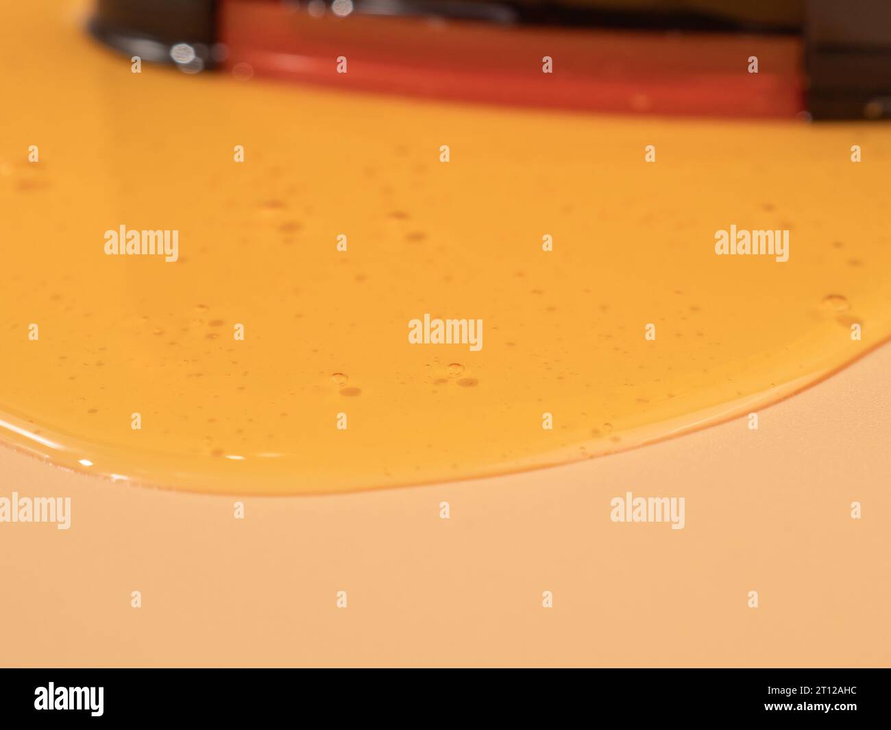 Liquid shower gel flows gracefully across a bright orange background ...