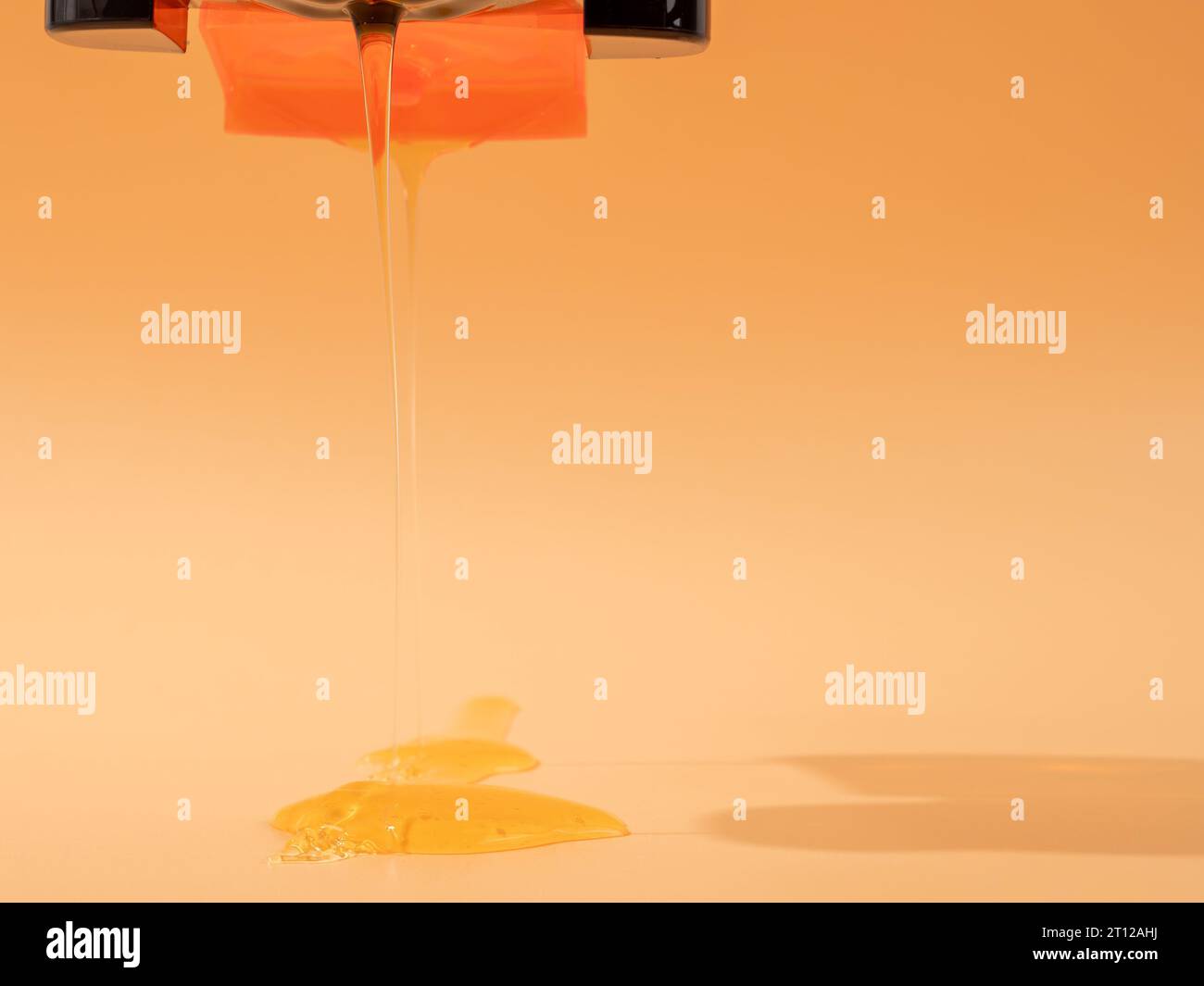 Liquid shower gel flows gracefully across a bright orange background ...
