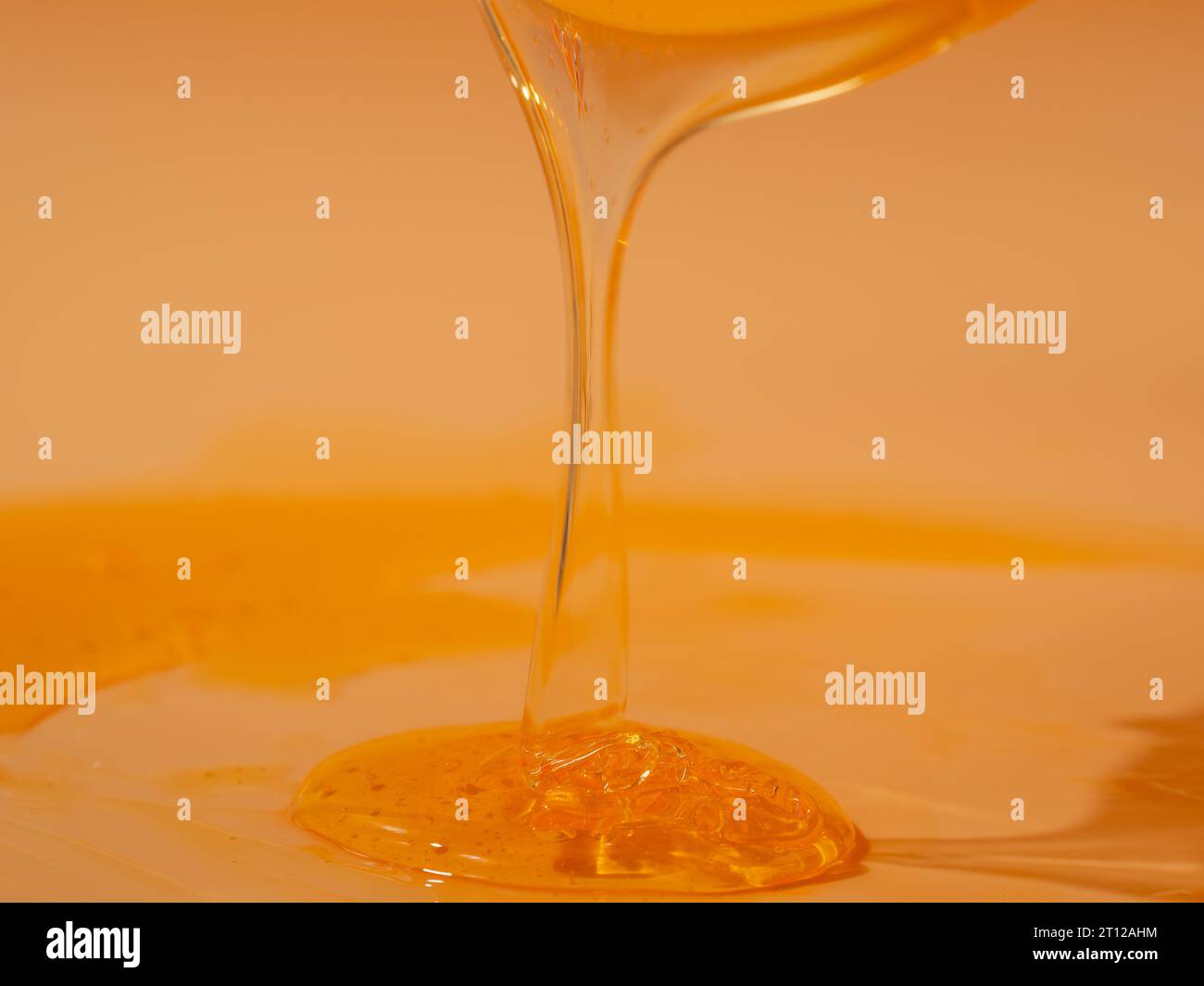 Liquid shower gel flows gracefully across a bright orange background ...