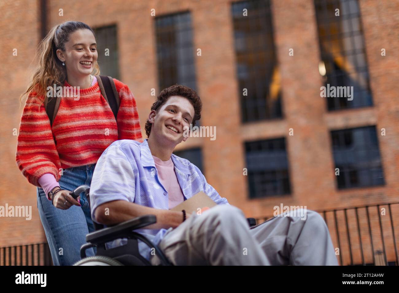 Handsome gen Z boy in wheelchair with friend in the city. Inclusion ...