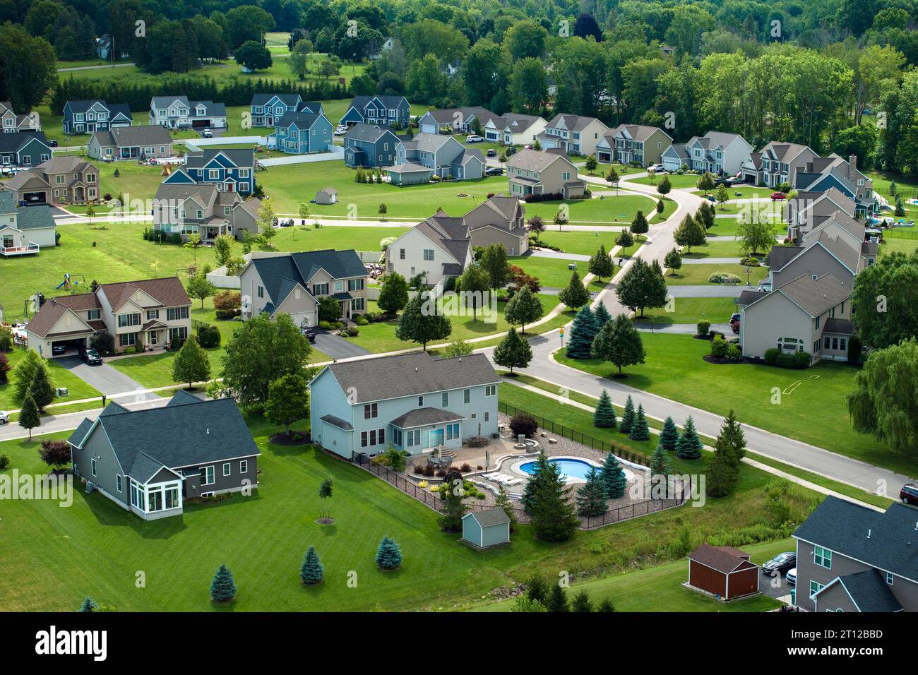 Upscale suburban homes with large backyards and green grassy lawns in summer season. Private ...