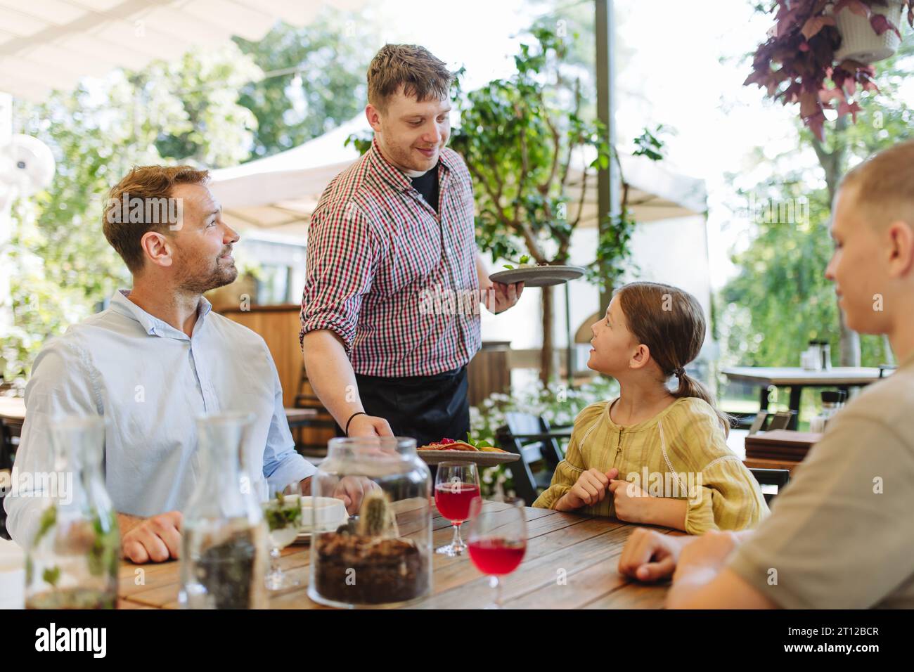 Waiter bringing food to the table in the restaurant Stock Photo - Alamy