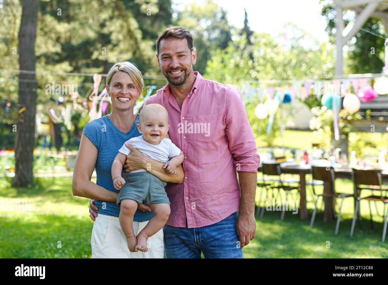 Young family with baby at family garden party. Father, mother, and ...