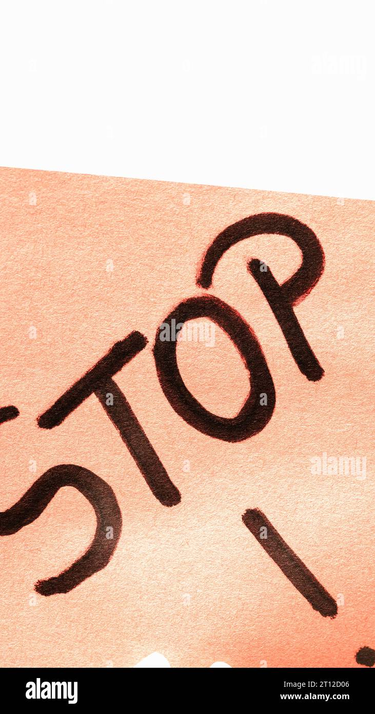 Stop handwriting text close up isolated on orange paper with copy space ...