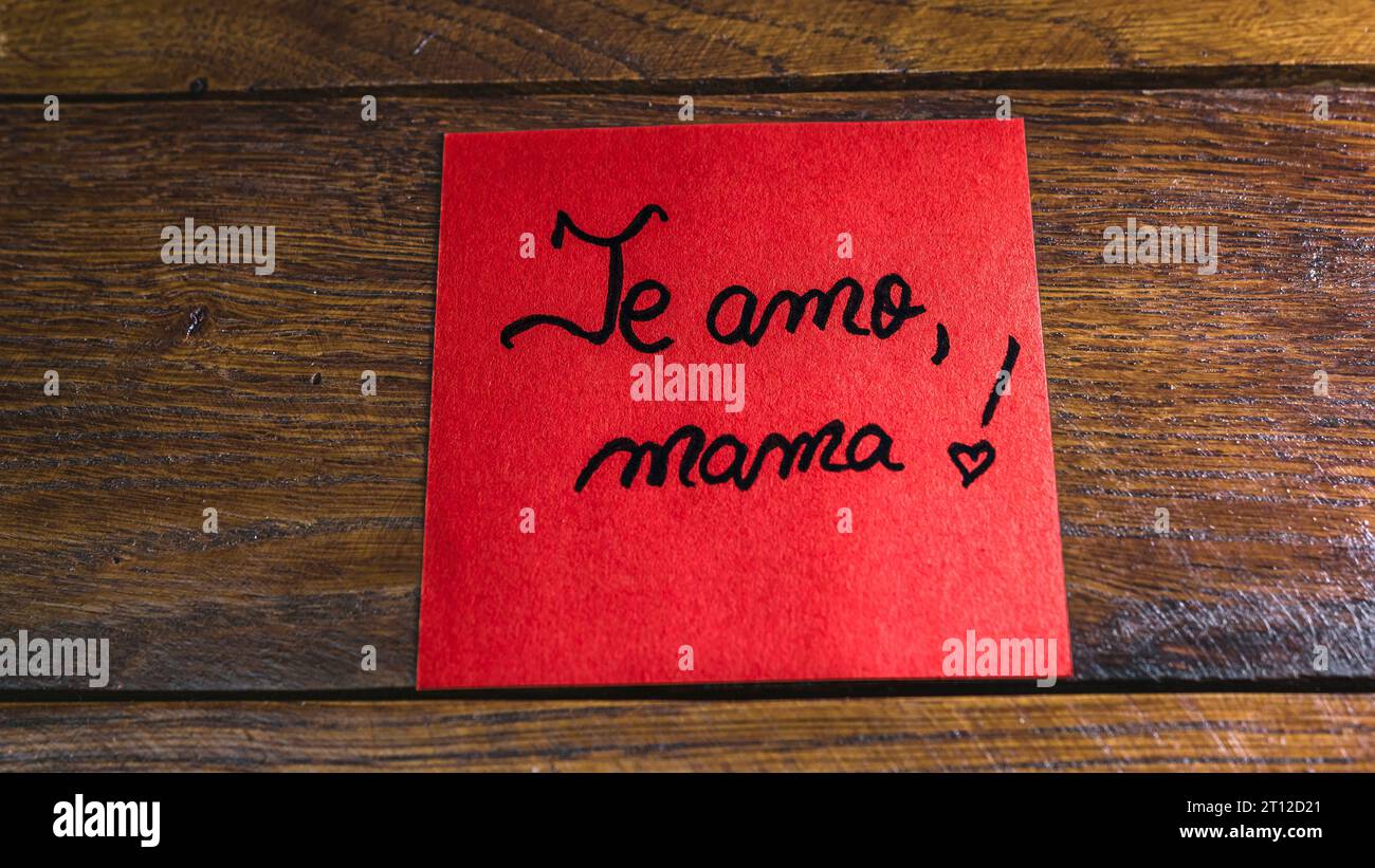 Writing I love you, mom in Spanish (te amo, mama) on memo post reminder ...