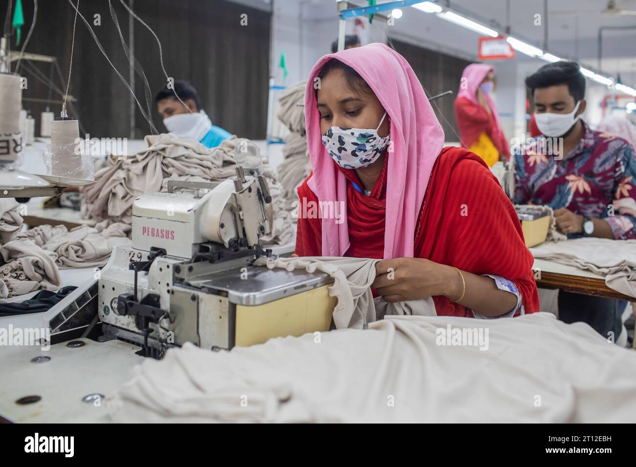 Garment workers work in a sewing section at the Surma Garments Limited ...