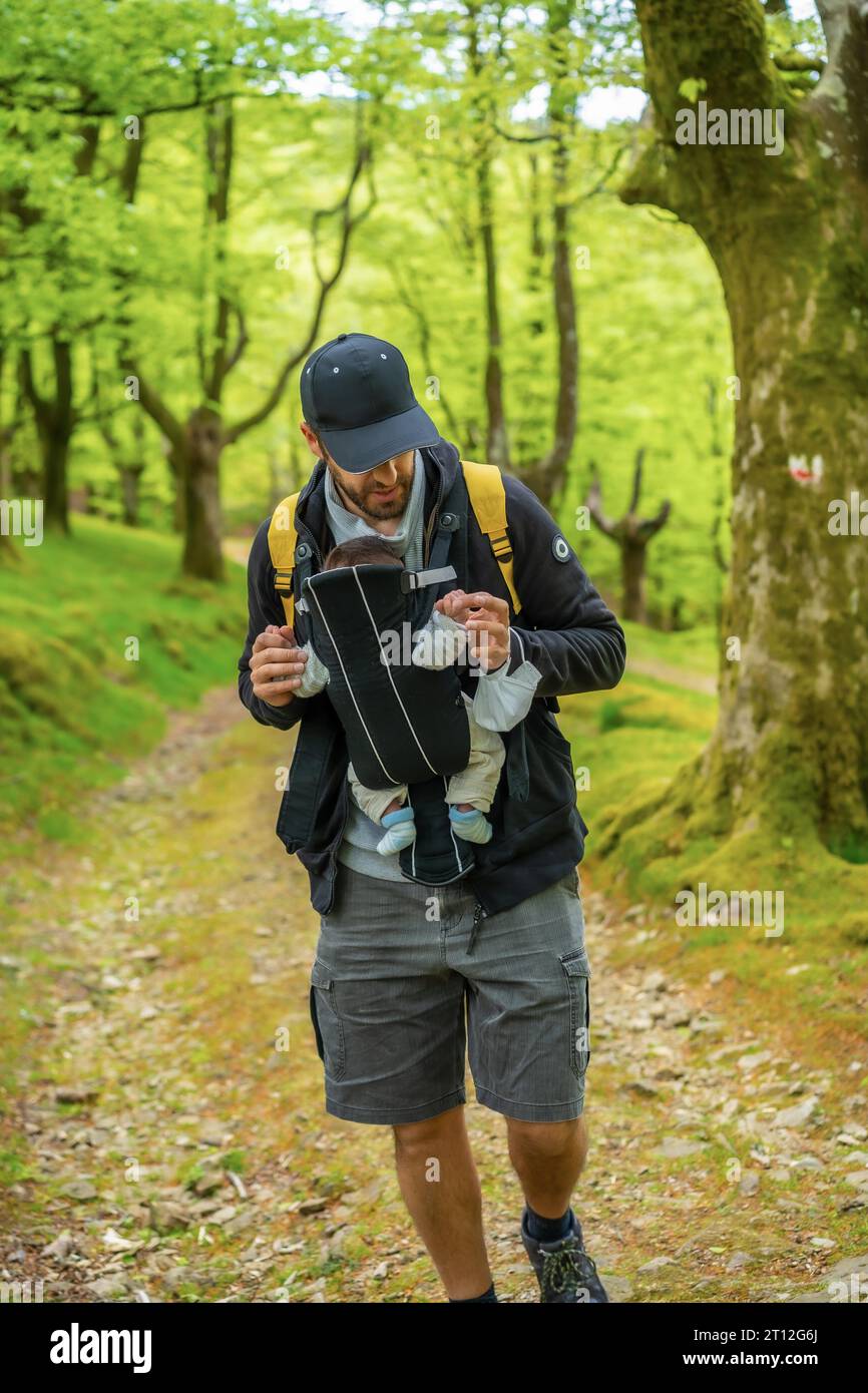 A young father with a yellow backpack walking with the newborn child in ...