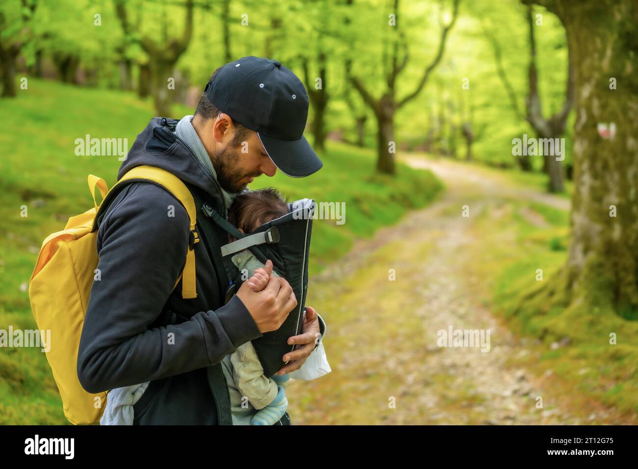 A young father with a yellow backpack walking with the newborn child in ...