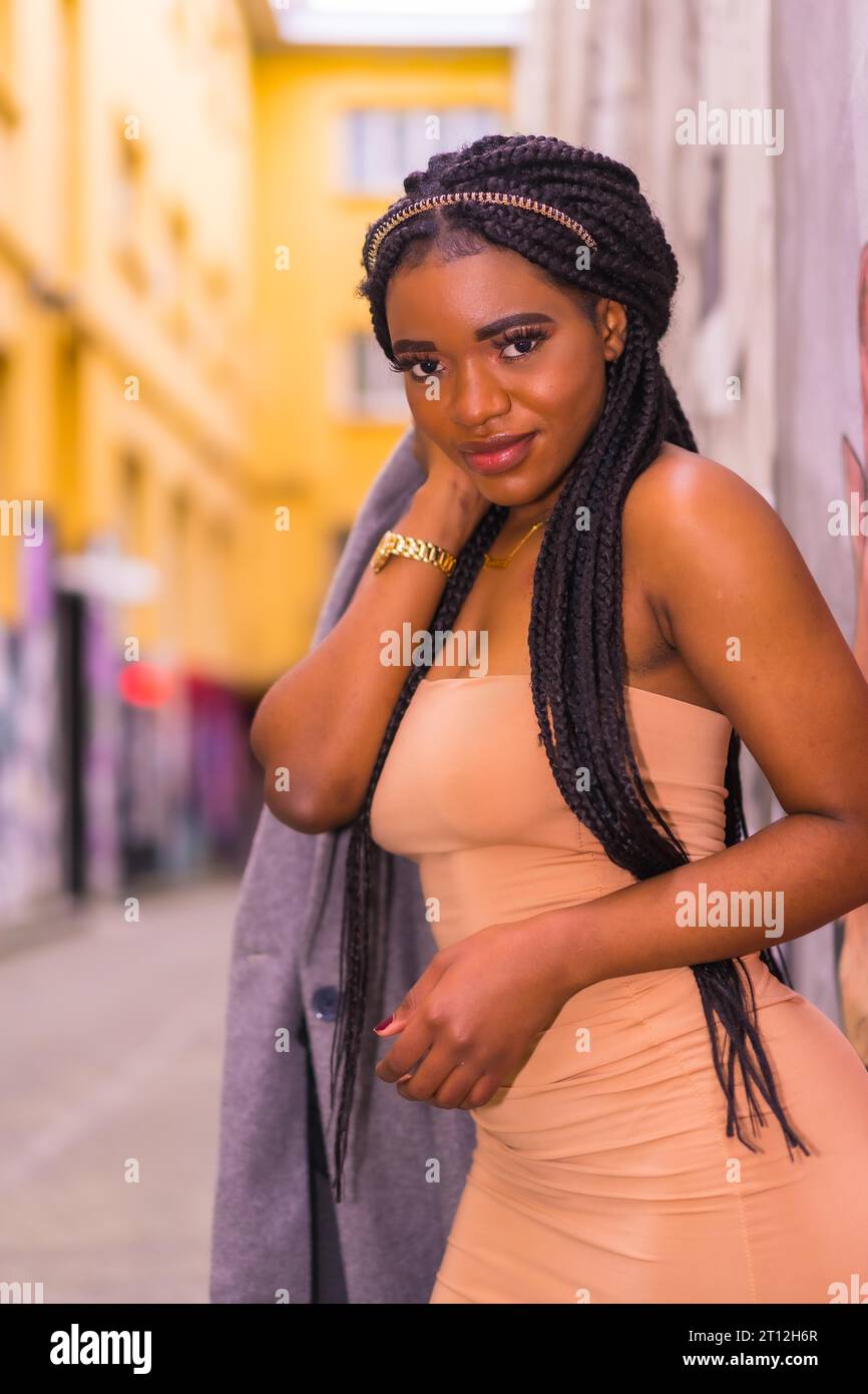 Trendy urban style with a black African girl in a cream colored dress on a city street. Portrait ...