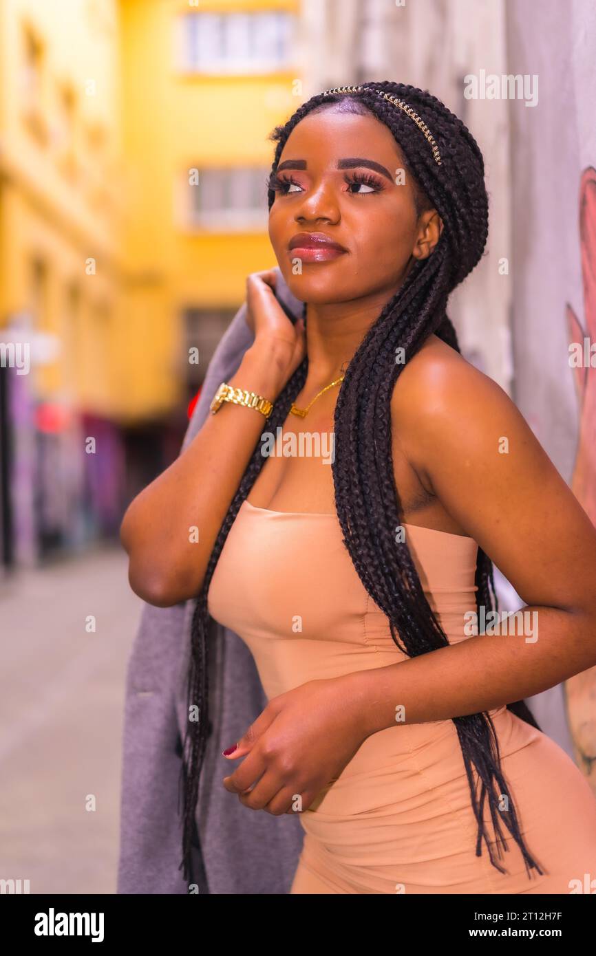 Trendy urban style with a black African girl in a cream colored dress on a city street. Portrait ...
