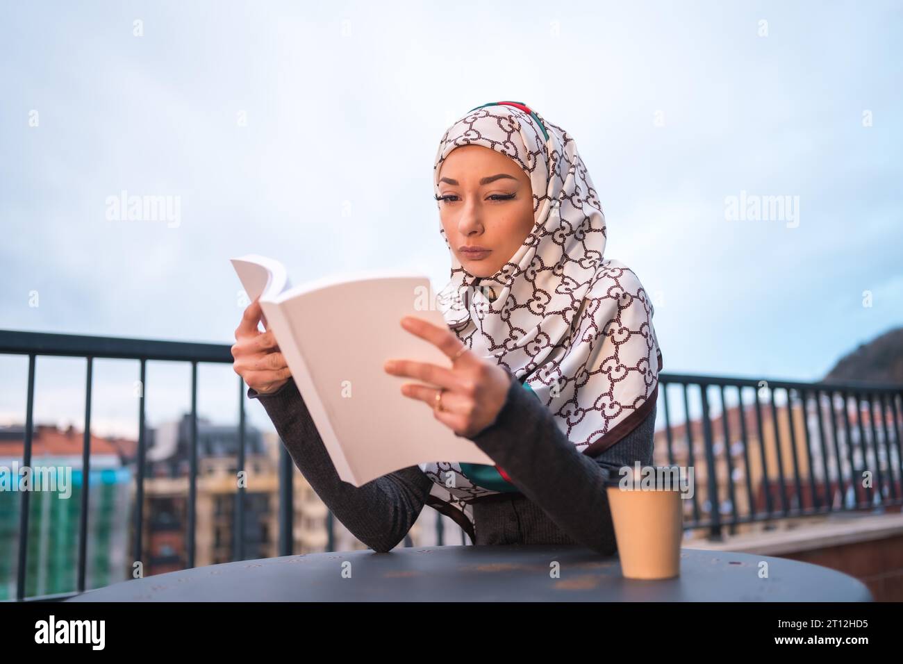 Arab girl with white veil at the computer on the terrace of a coffe ...