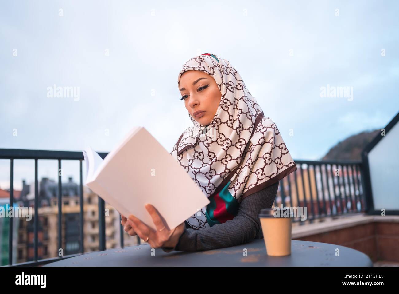 Arab girl with white veil at the computer on the terrace of a coffe ...