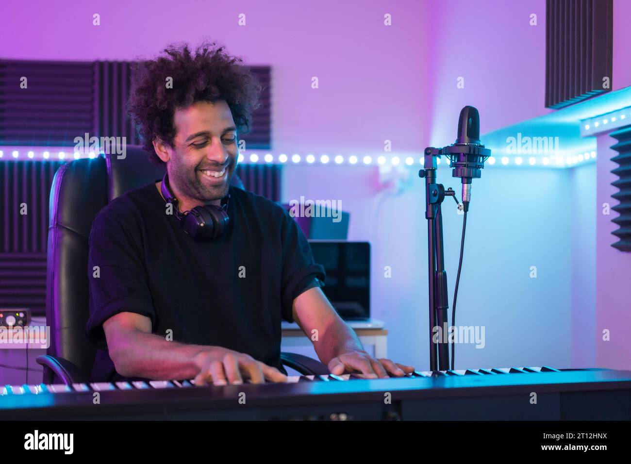 Frpntal view of a happy musician playing an electronic piano in a ...