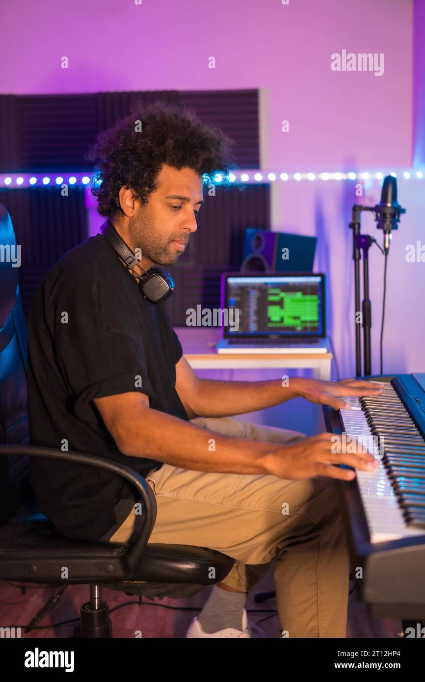 Vertical photo of a musician playing piano and recording in a modern ...