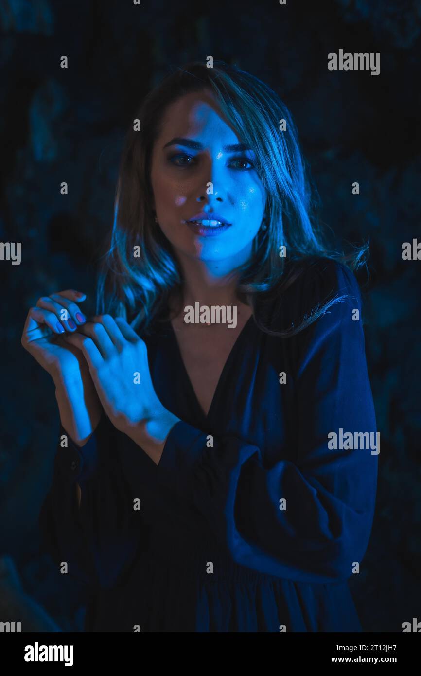 Lifestyle, portrait of a caucasian girl in a cave with blue led light ...