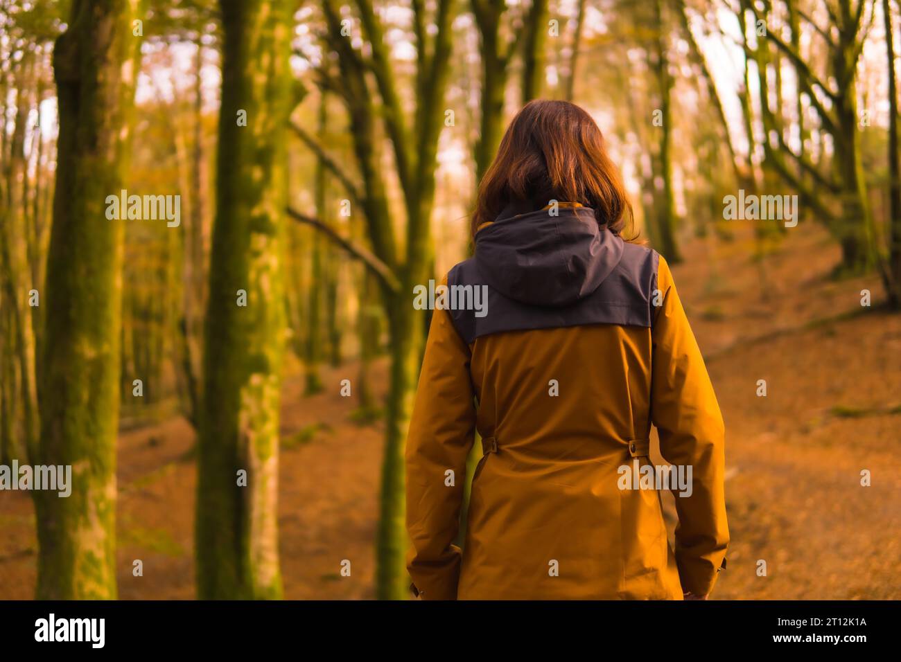Lifestyle, a young woman in a yellow jacket walking backwards along a ...