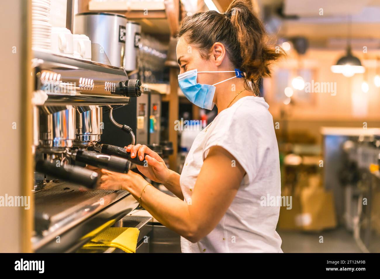 A dark-haired Caucasian waitress with face mask in a bar. New normality ...
