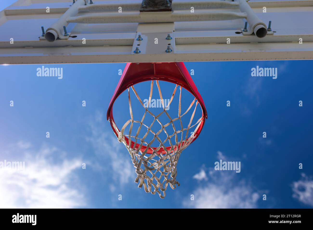 A basketball hoop with a net on a court against a backdrop of blue ...