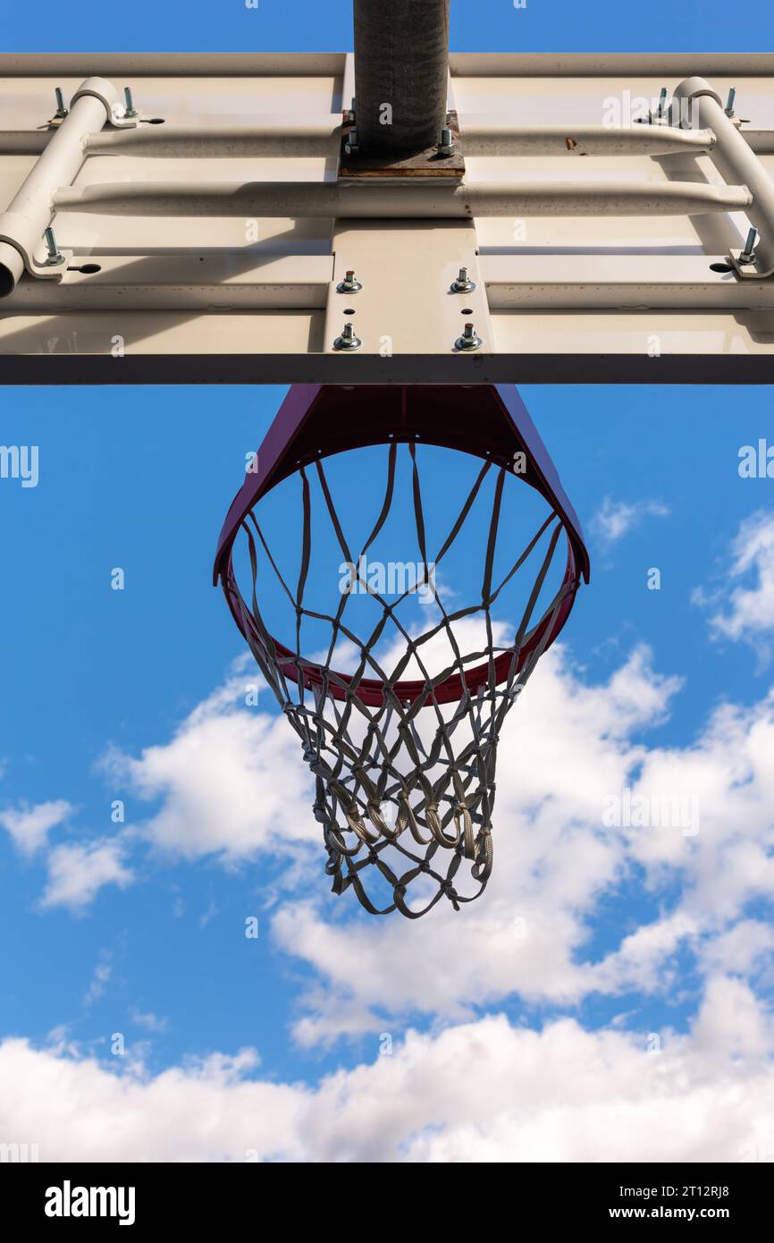 A basketball hoop with a net on a court against a backdrop of blue ...