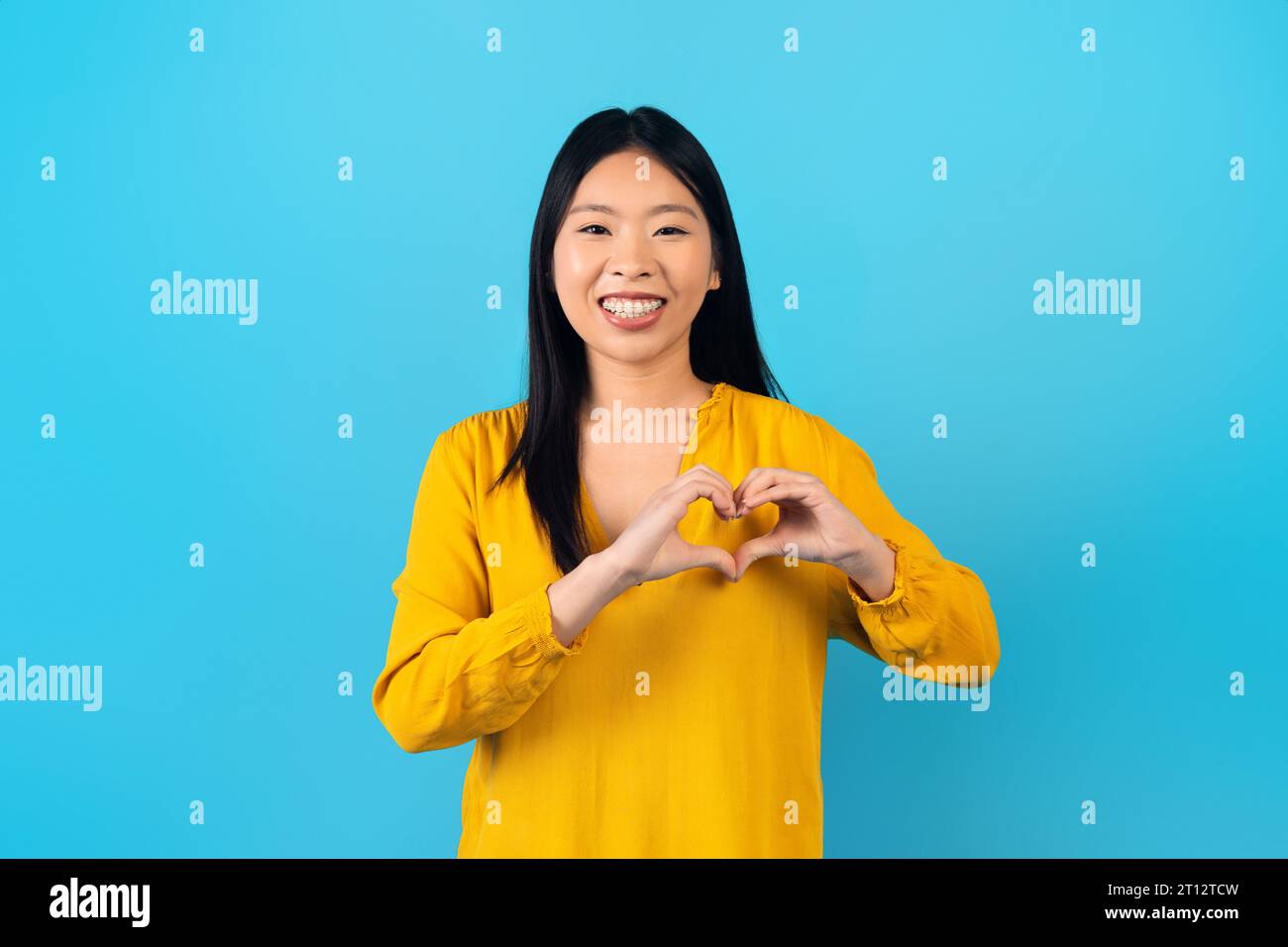 Happy young korean woman holding hands over heart, showing love Stock ...