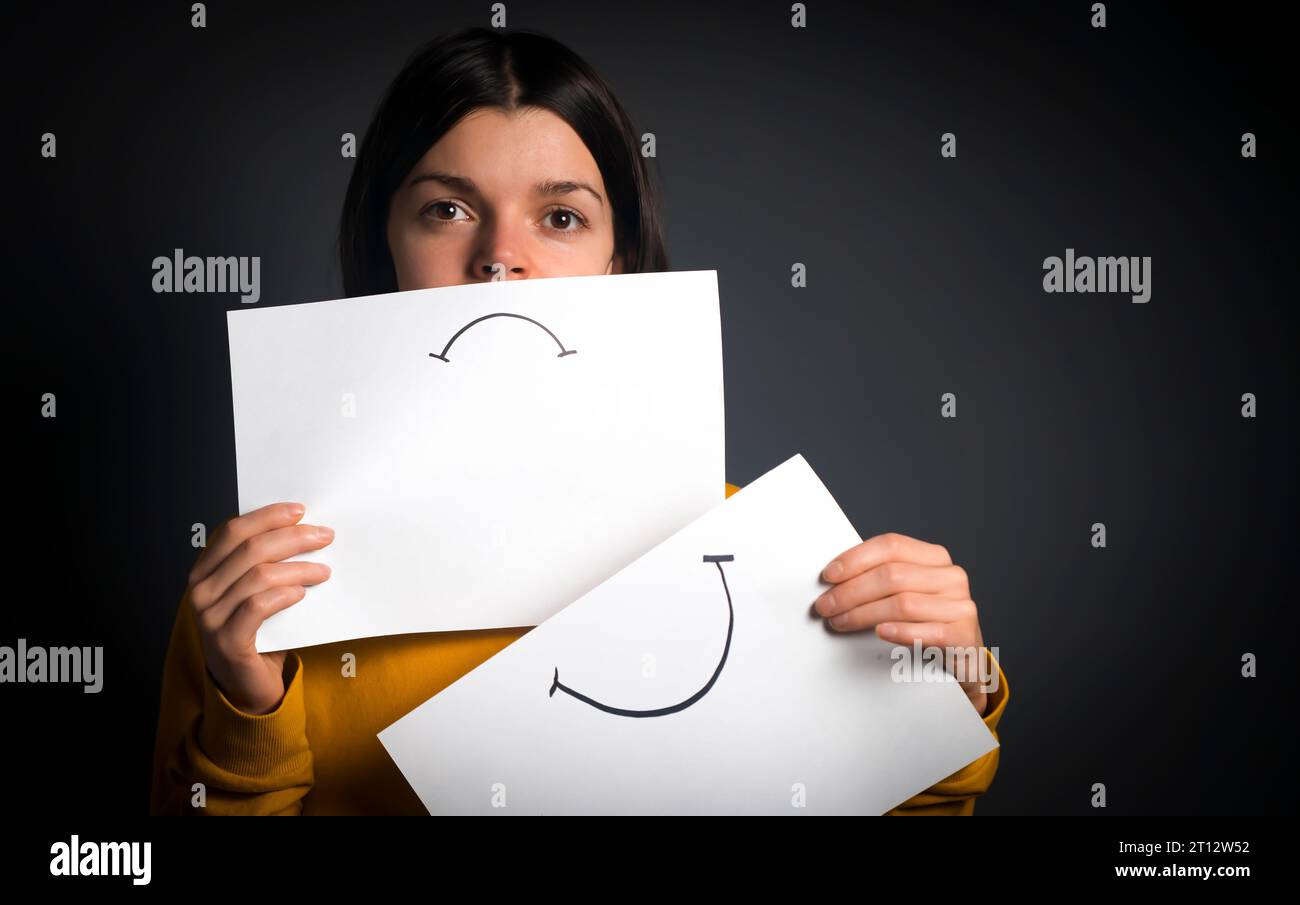 Girl is hiding emotions, holding 2 papers with smile and sadness Stock ...