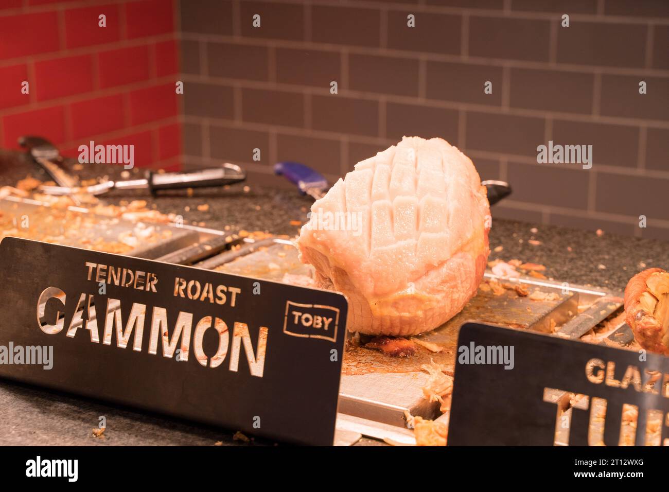 Tender roast Gammon on heated serving counter to be sliced for customer ...