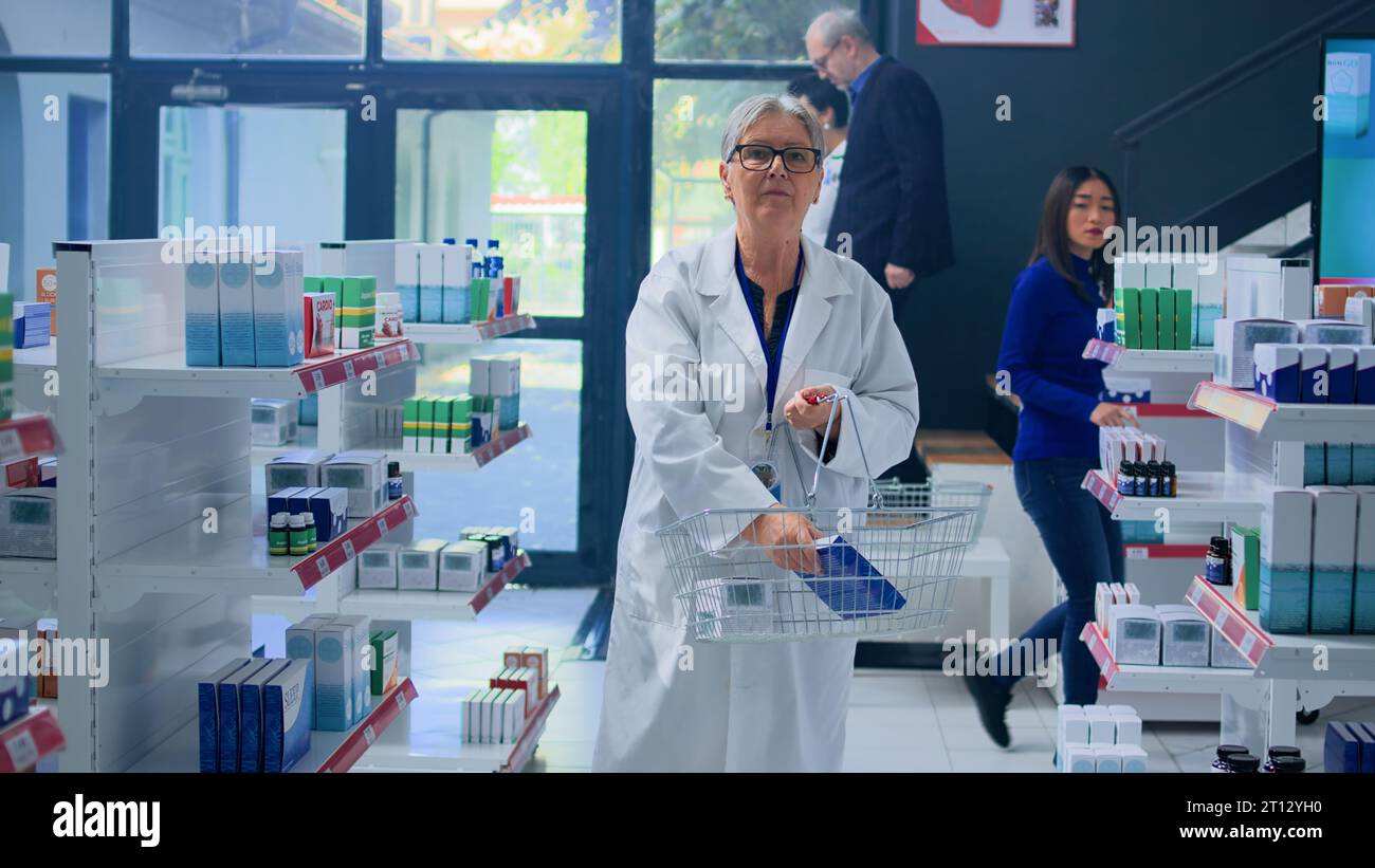 Elderly experienced pharmacologist in apothecary holding shopping ...