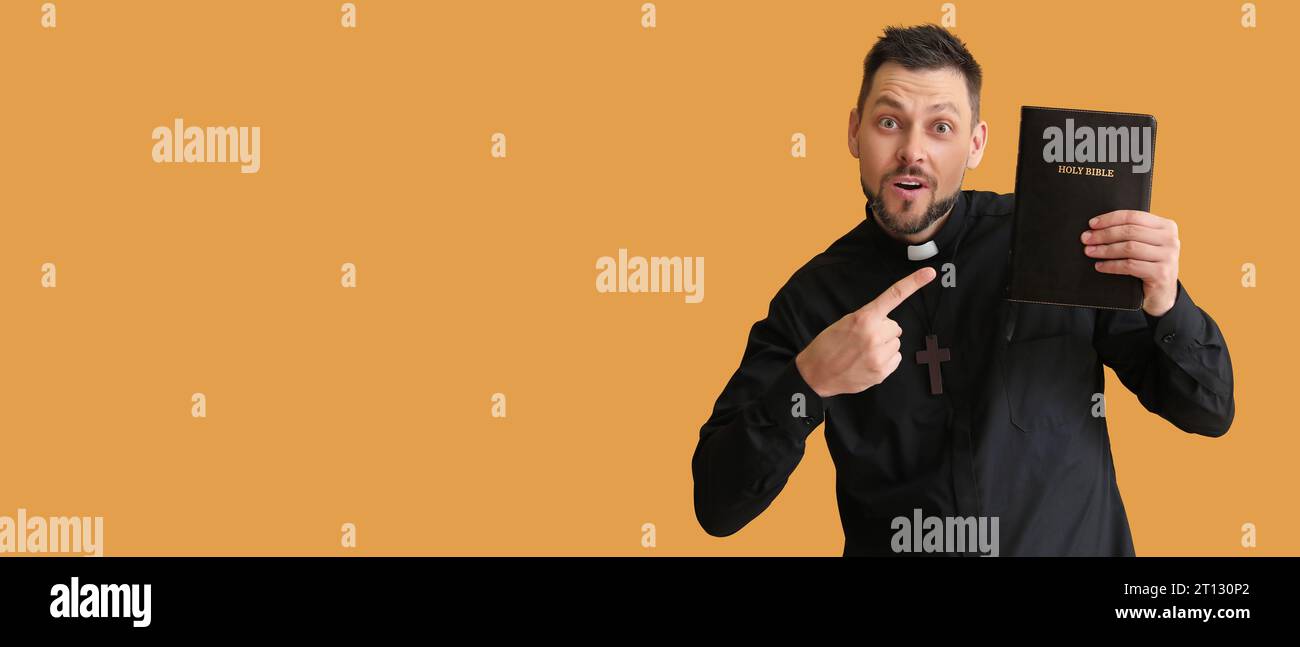 Surprised priest holding Bible on orange background with space for text ...