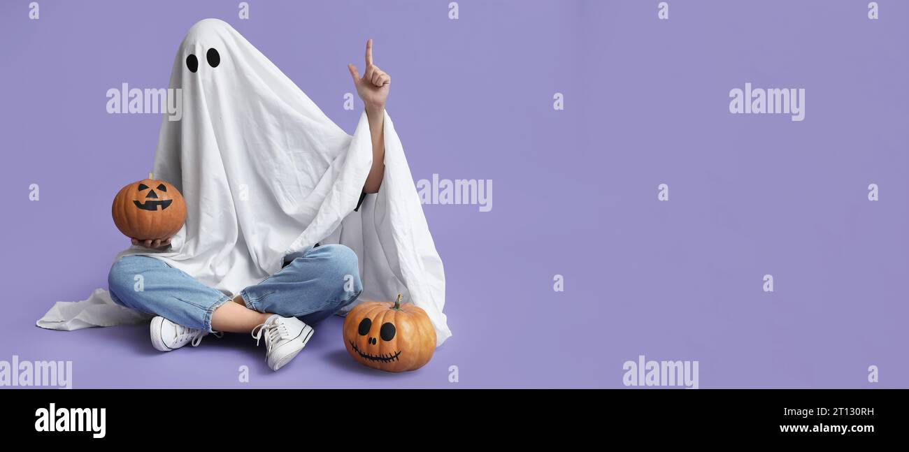Person in costume of ghost and with Halloween pumpkins pointing at ...